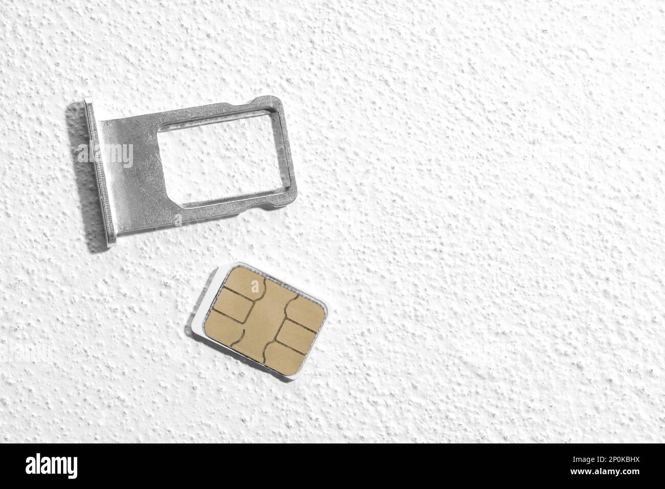 SIM card and tray on white stone background, flat lay. Space for text ...