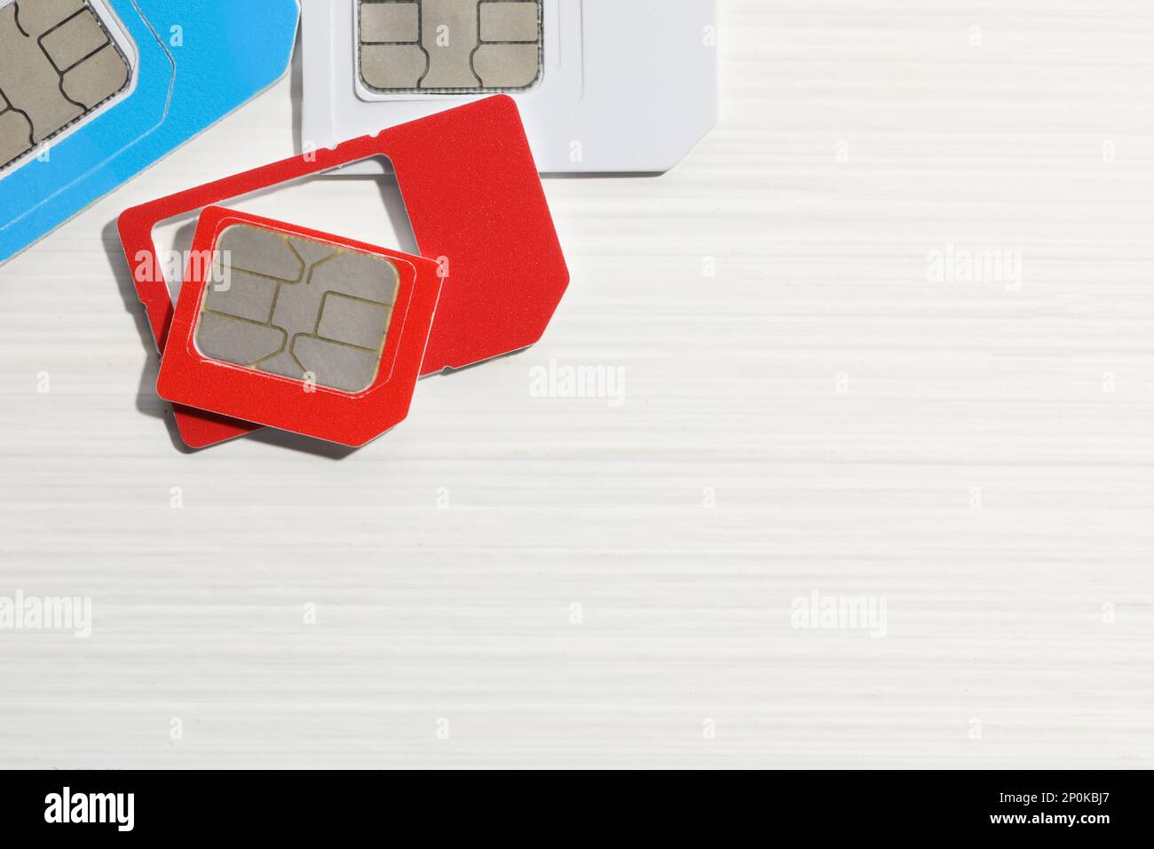 Different SIM cards on white wooden background, flat lay. Space for ...