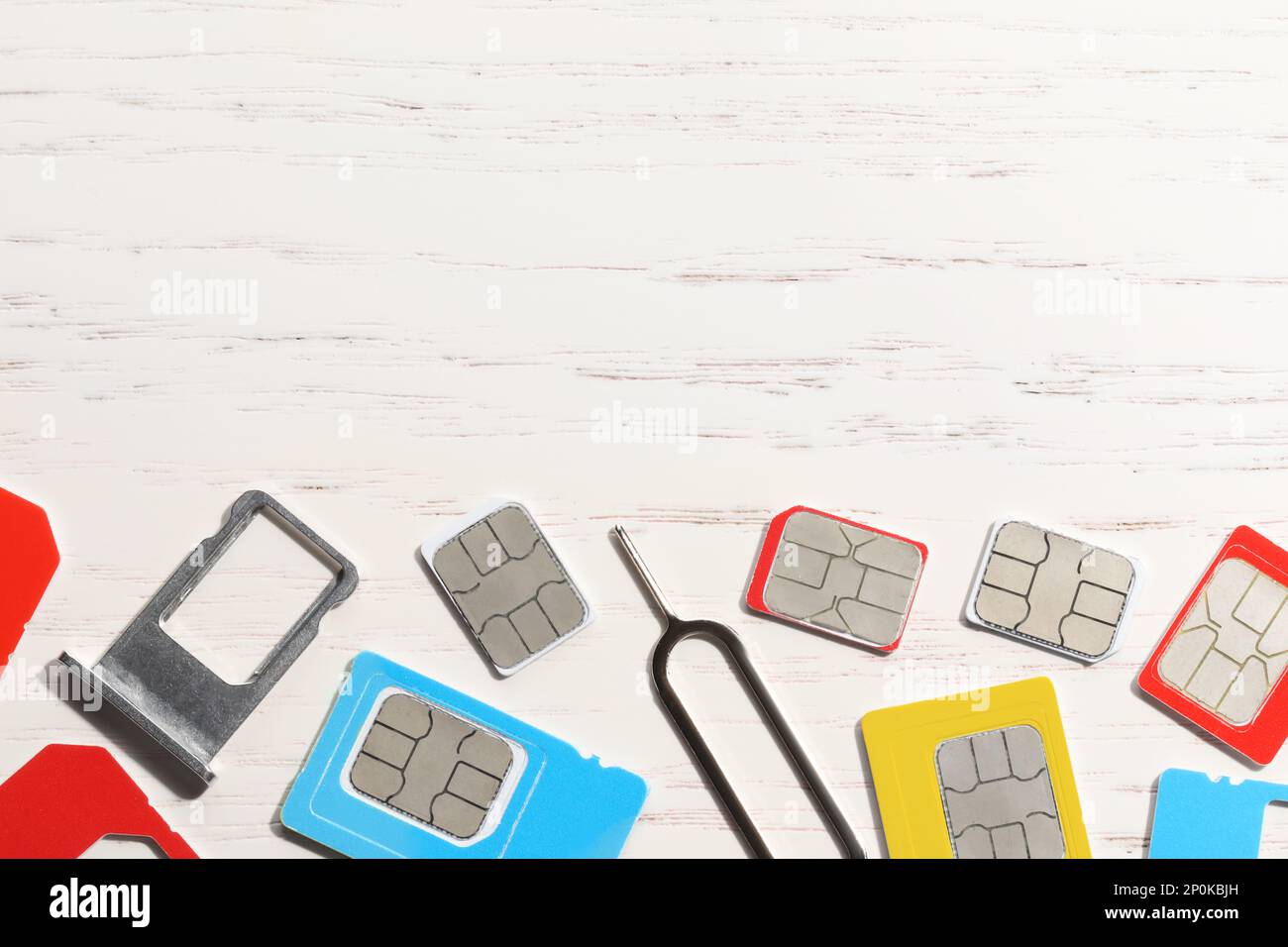 Different SIM cards, ejector and tray on white wooden background, flat ...