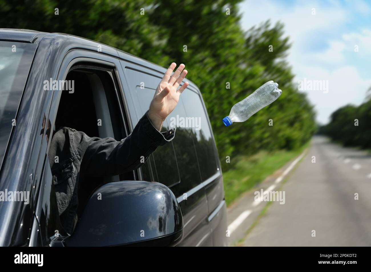 Driver throwing away plastic bottle from car window. Garbage on road ...