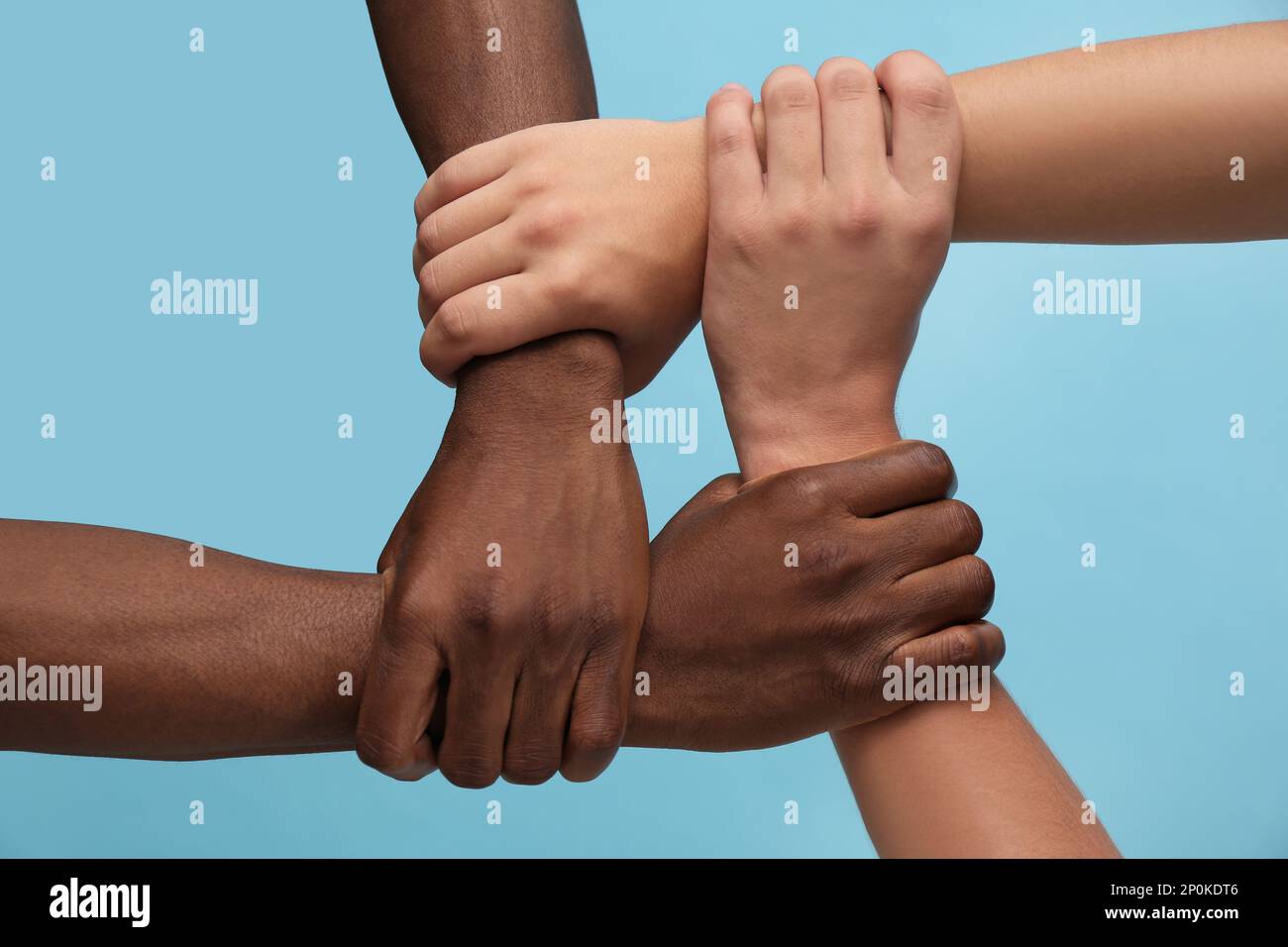 Men joining hands together on light blue background, closeup Stock ...