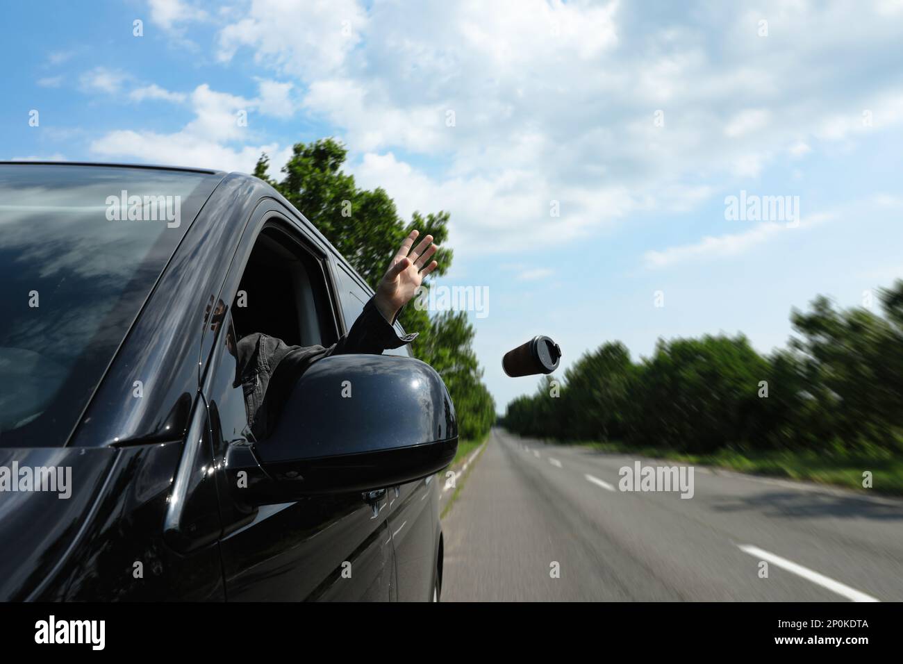 Driver throwing away paper coffee cup from car window. Garbage on road ...