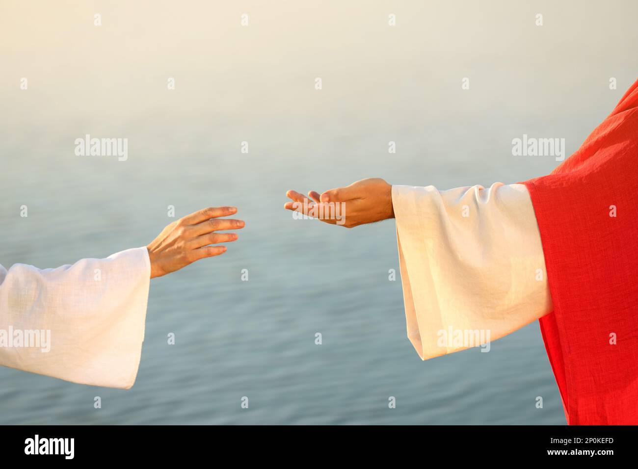 Woman reaching for Jesus Christ's hand near water outdoors, closeup ...