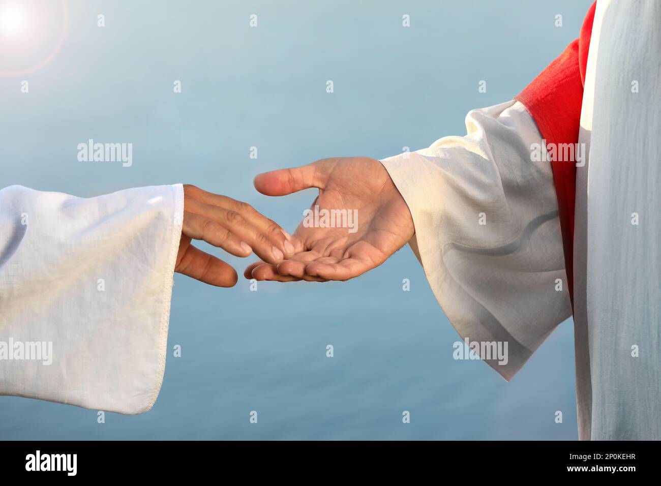 Man reaching for Jesus Christ's hand near water outdoors, closeup Stock ...