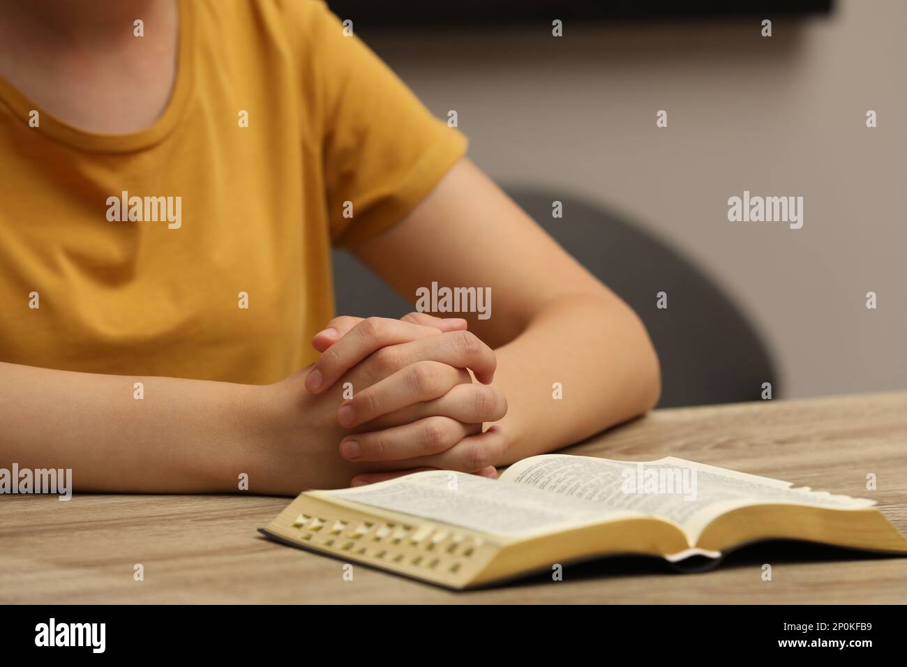 Religious woman praying over Bible at wooden table indoors, closeup ...