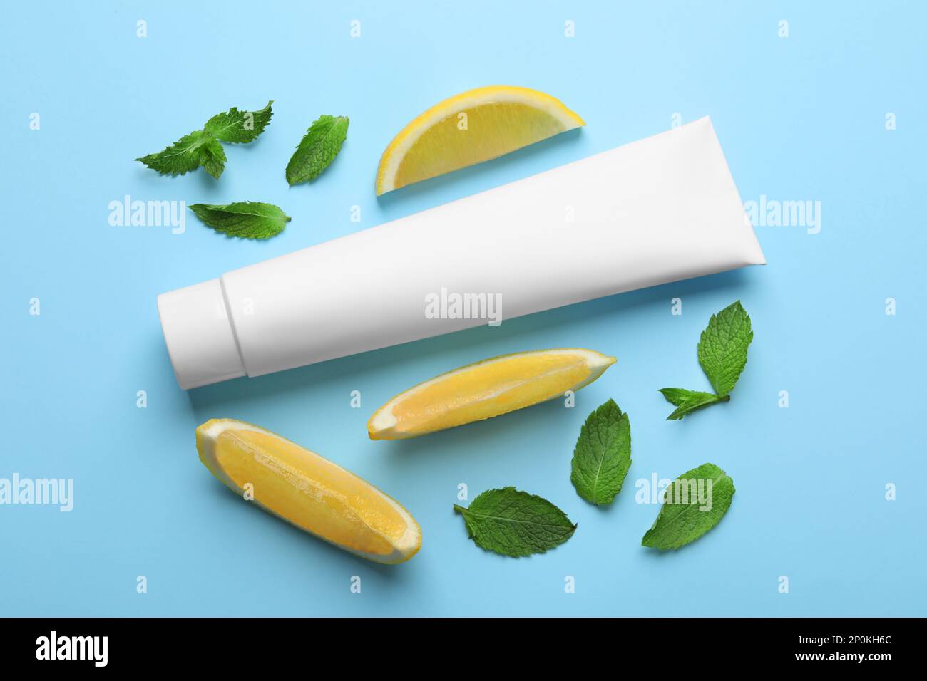 Blank tube of toothpaste with mint leaves and lemon slices on turquoise ...