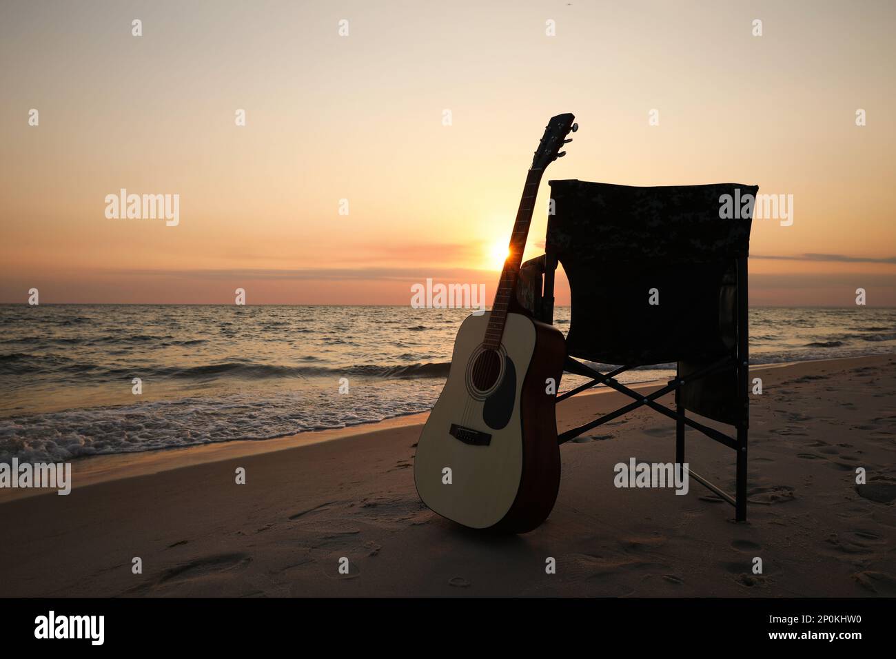 Camping chair and guitar on sandy beach near sea, space for text Stock ...