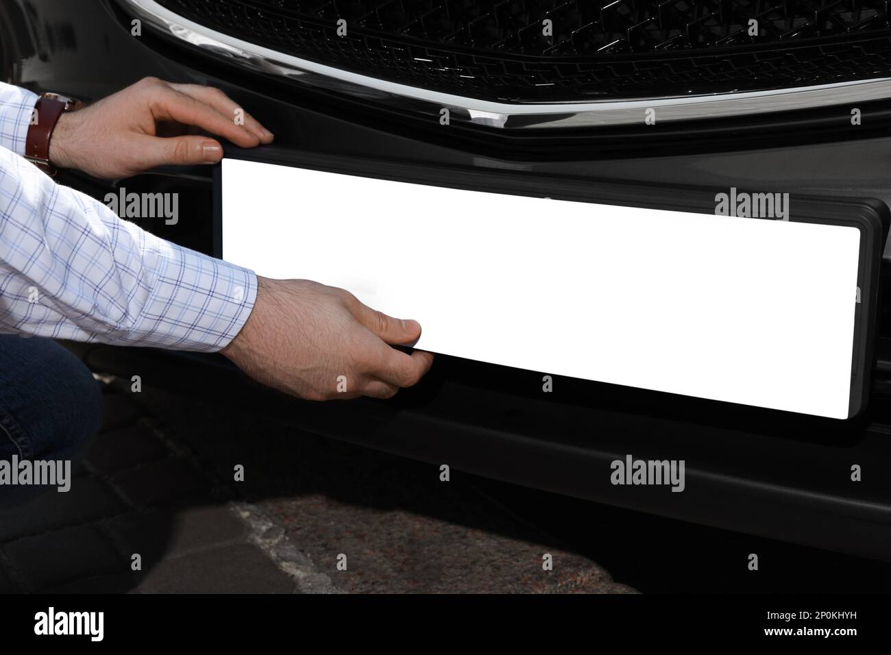Man installing vehicle registration plate outdoors, closeup. Mockup for ...