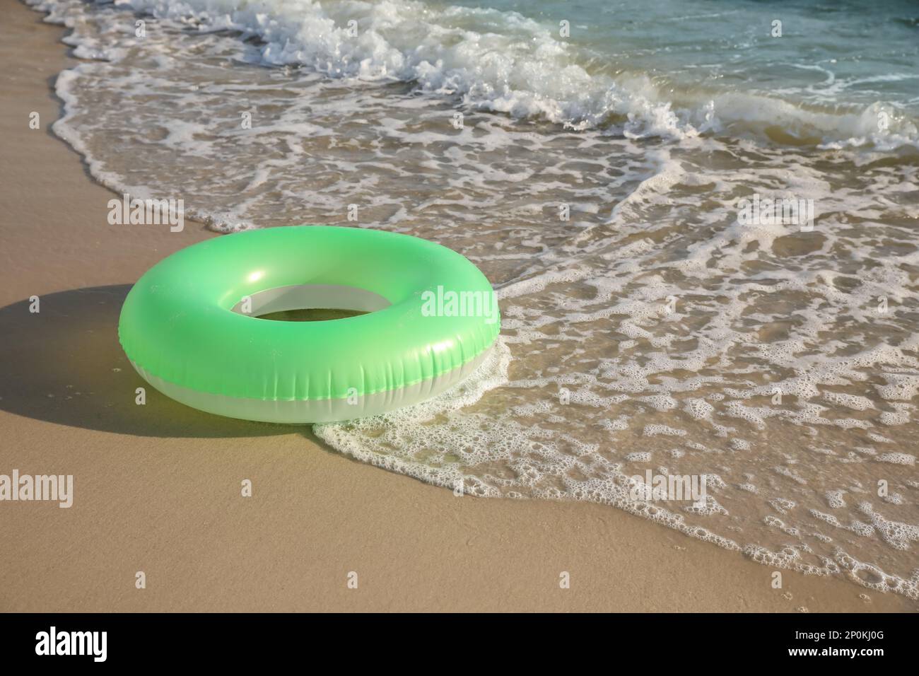Green inflatable ring on sandy beach near sea, space for text Stock ...