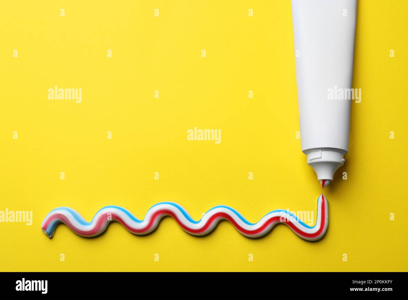 Blank tube with squeezed out toothpaste on yellow background, flat lay ...
