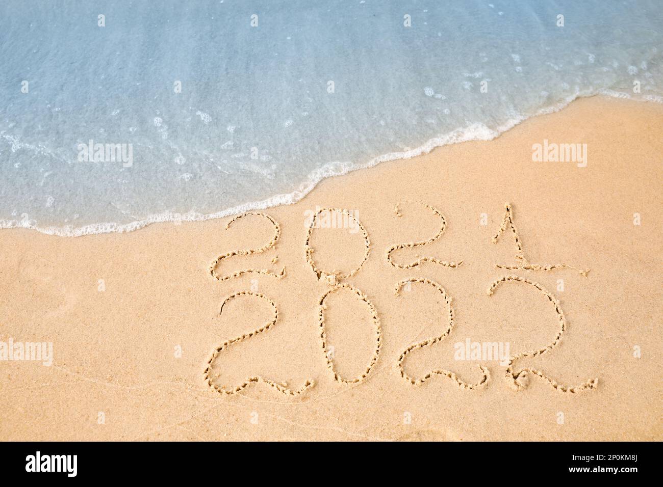 Dates written on sandy beach. 2021 washed by sea wave as New 2022 Year ...