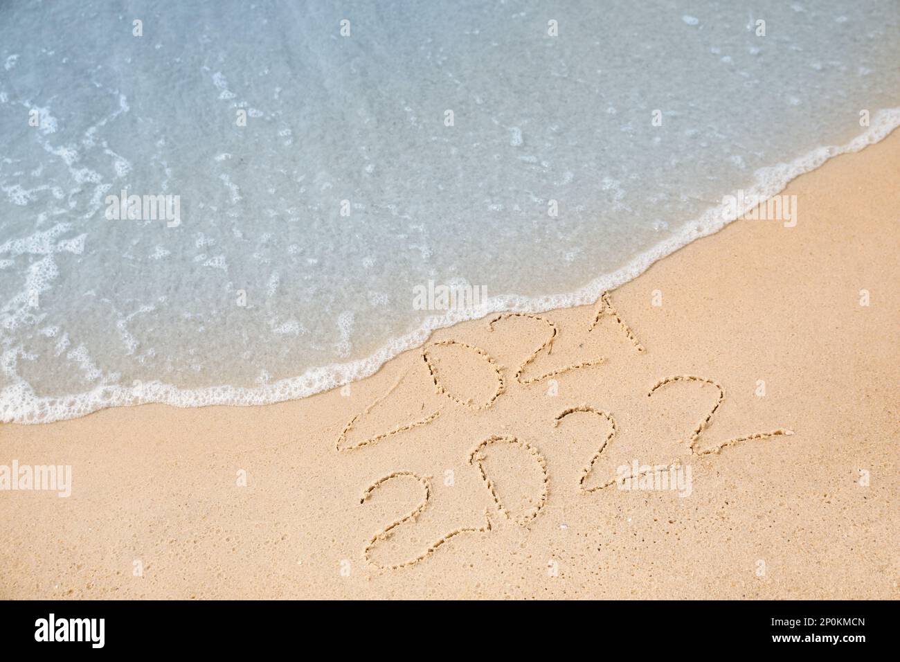 Dates written on sandy beach. 2021 washed by sea wave as New 2022 Year ...