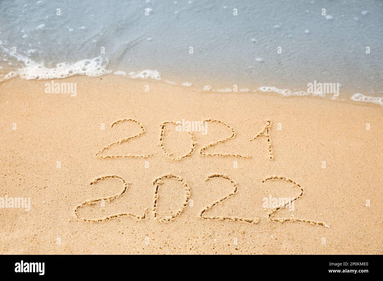Dates written on sandy beach. 2021 washed by sea wave as New 2022 Year ...
