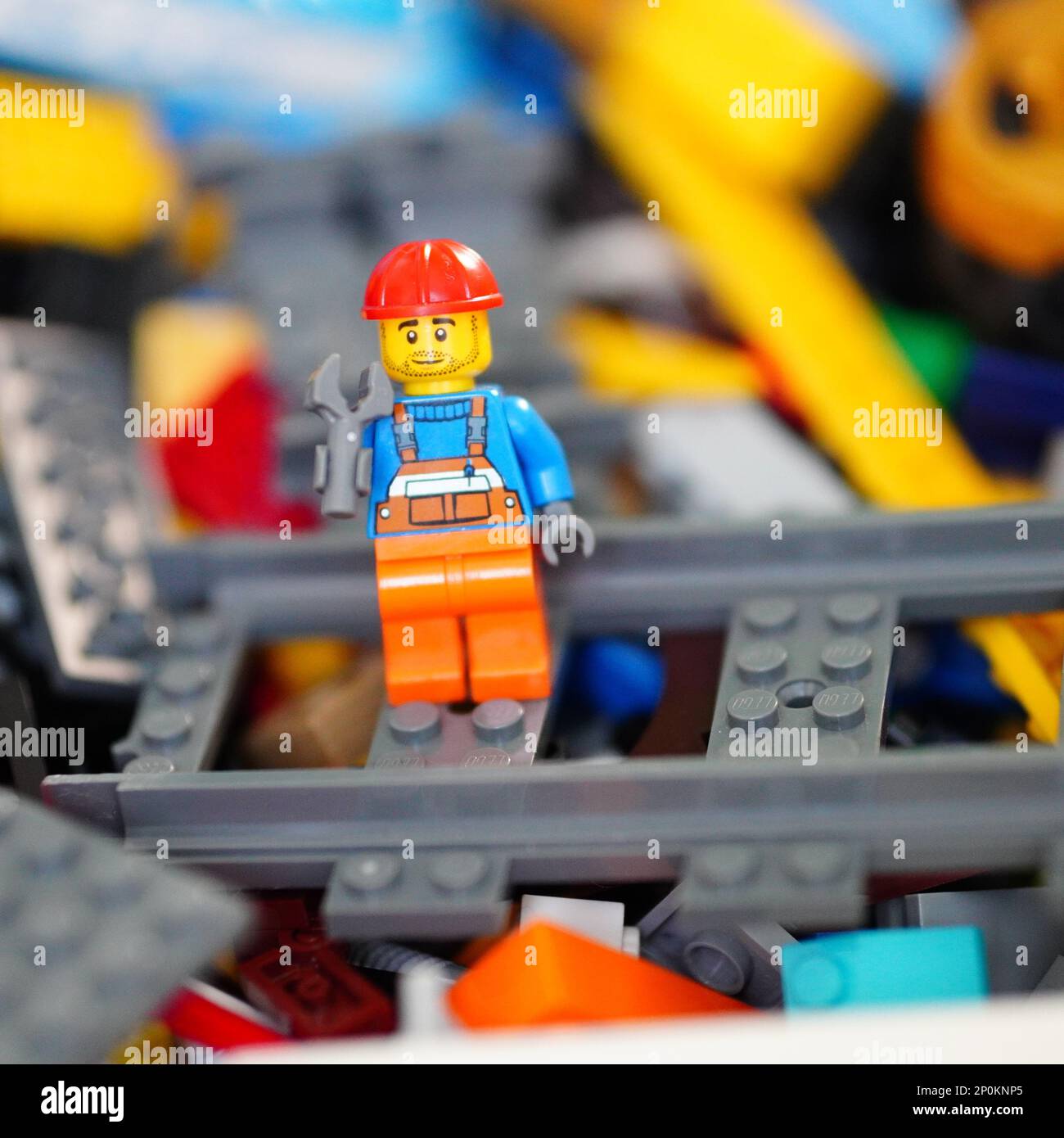 A Lego worker figurine standing on a lego train rack holding a ranch ...