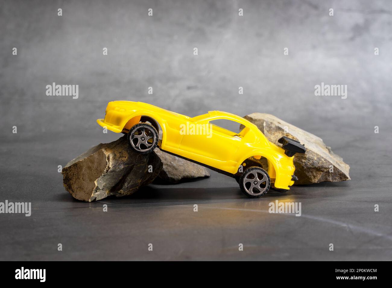 toy yellow car model on the rock dark background, traveling and ...