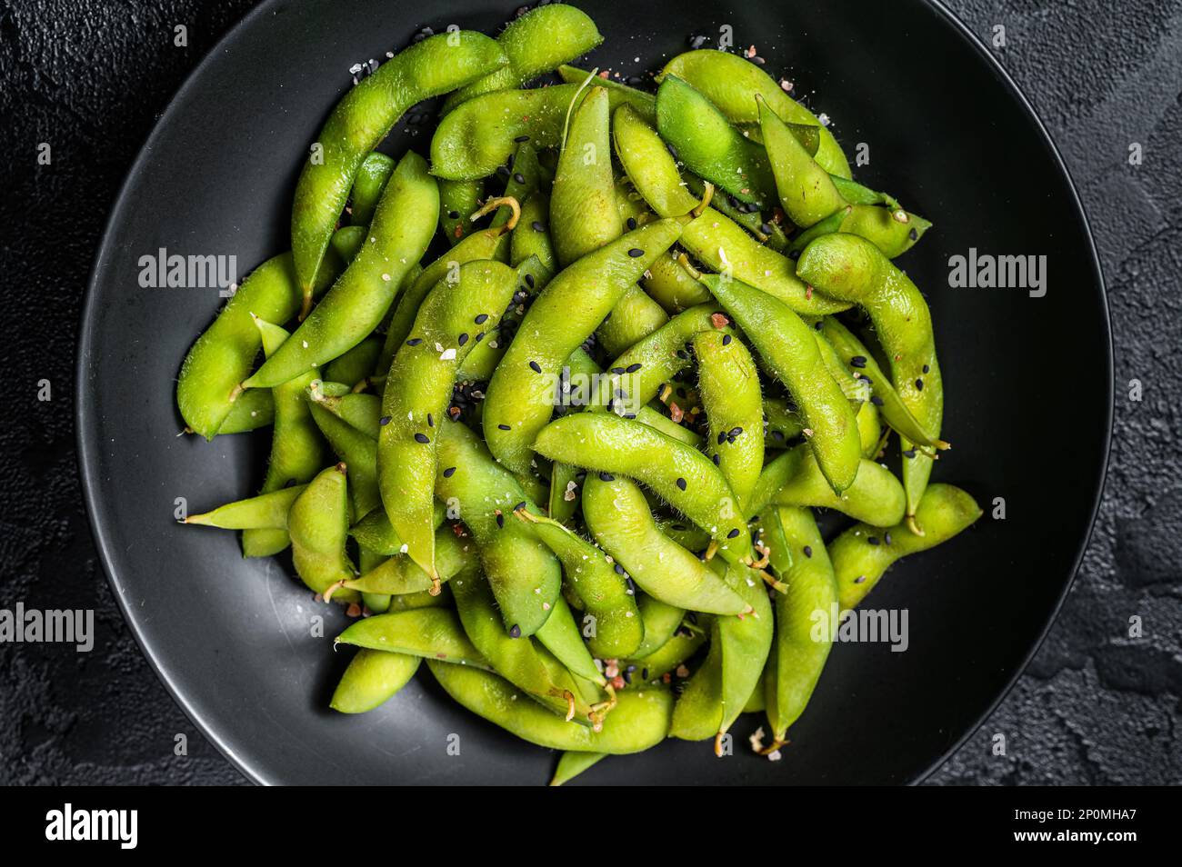Boiled Edamame Soy Beans with sea salt in a plate. Black background ...