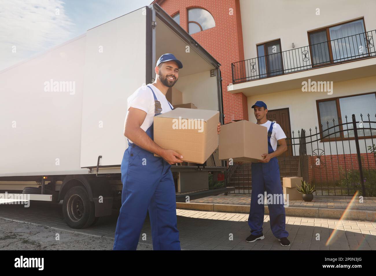 Workers unloading boxes from van outdoors. Moving service Stock Photo ...