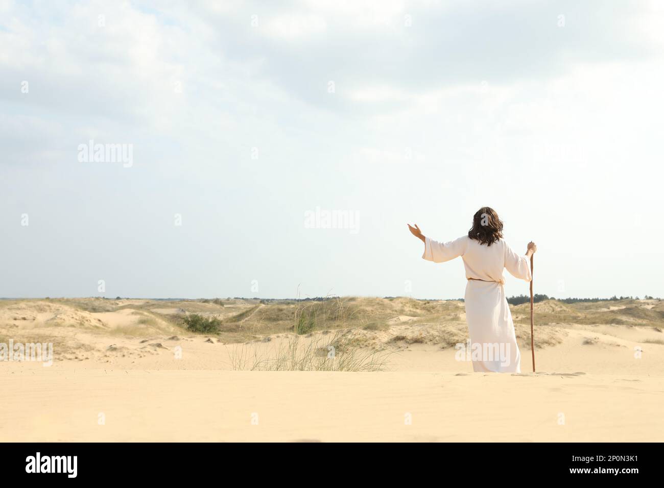 Jesus Christ raising hand in desert, back view. Space for text Stock ...