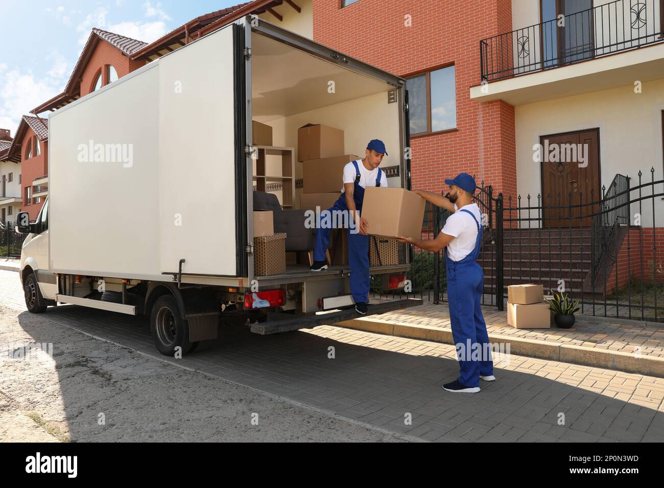Workers unloading boxes from van outdoors. Moving service Stock Photo ...