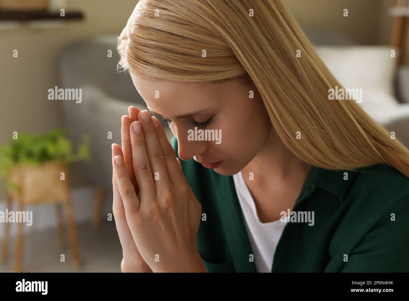 Religious young woman with clasped hands praying indoors Stock Photo ...