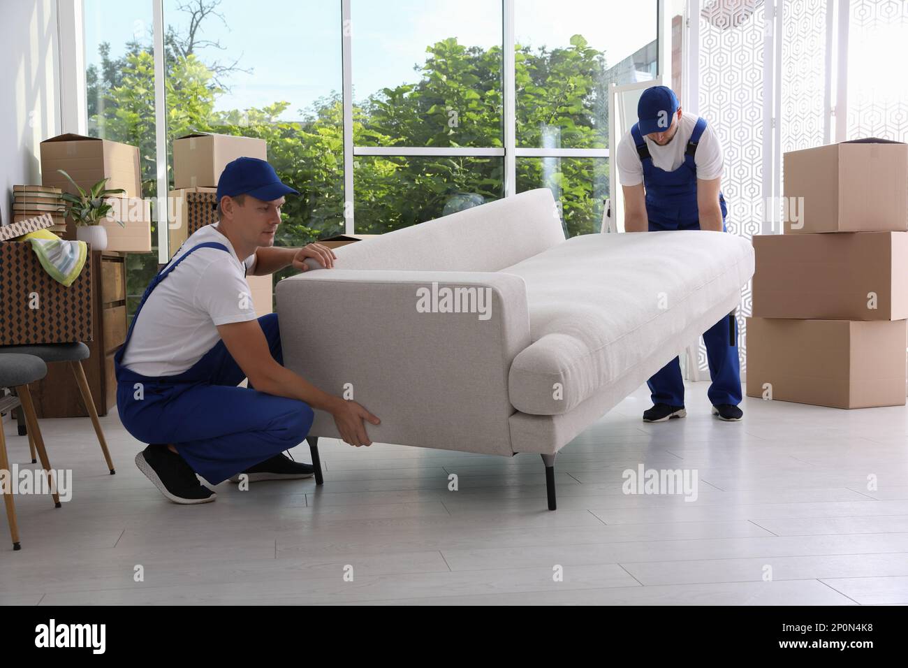 Moving service employees carrying sofa in room Stock Photo - Alamy