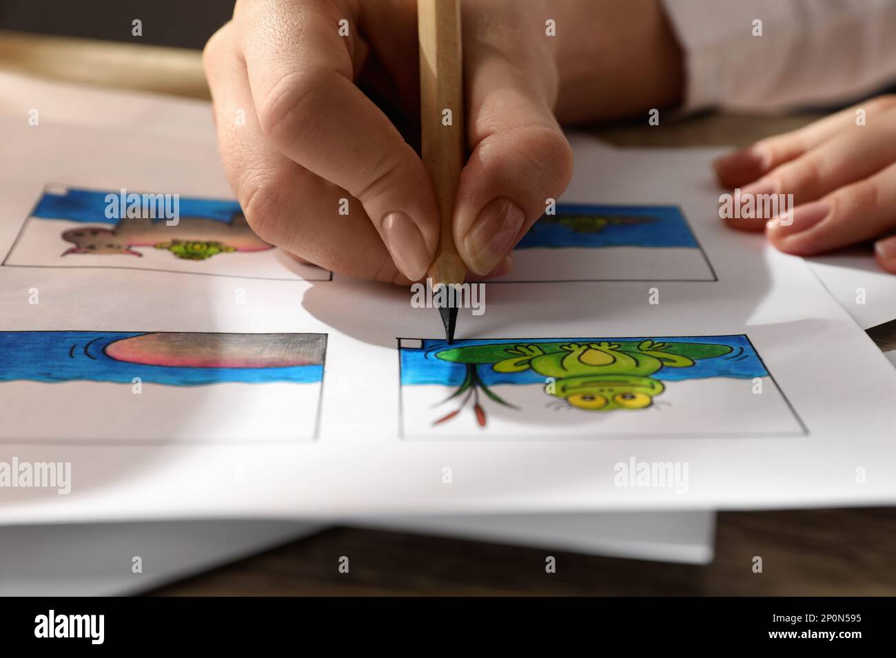 Woman drawing cartoon sketch in storyboard at workplace, closeup. Pre ...