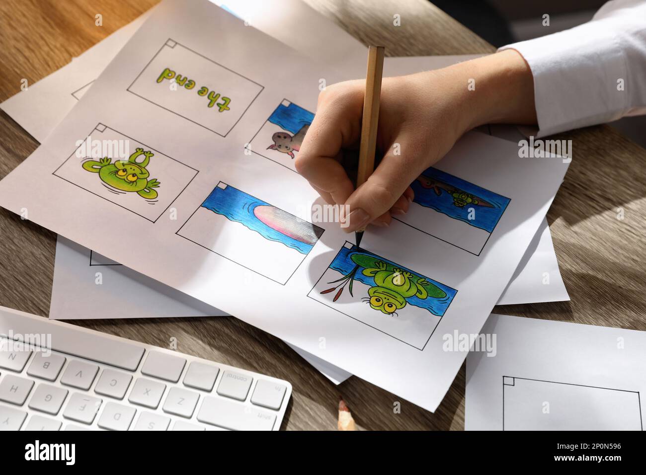 Woman drawing cartoon sketch in storyboard at workplace, closeup. Pre ...
