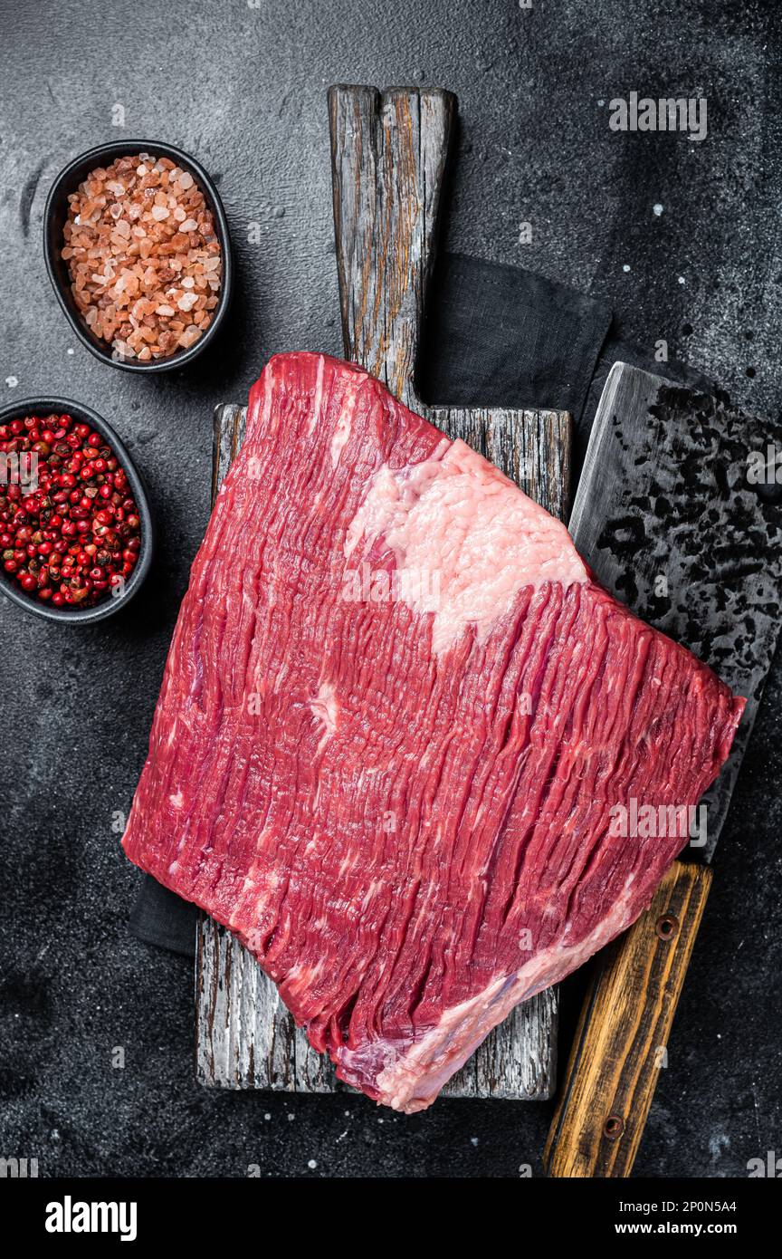 Uncooked Raw beef brisket meat on butcher board. Black background. Top ...