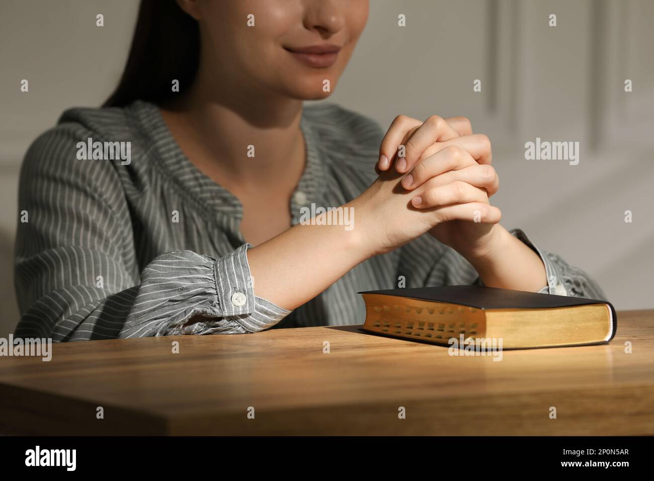 Religious woman praying over Bible at wooden table indoors, closeup ...