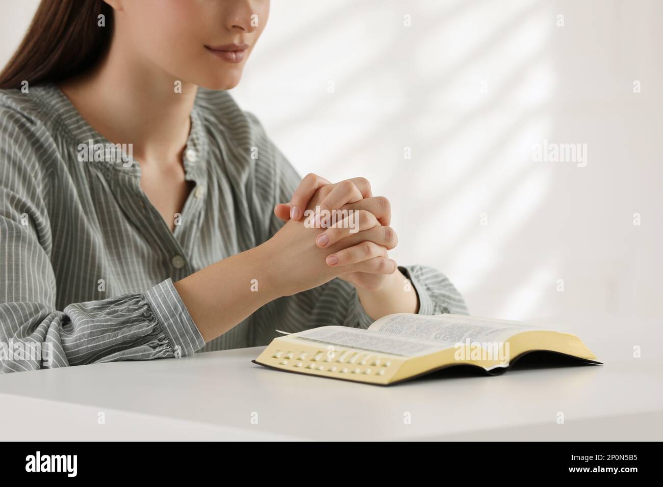 Religious woman praying over Bible at table indoors, closeup Stock ...