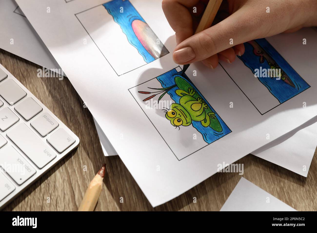 Woman drawing cartoon sketch in storyboard at workplace, closeup. Pre ...