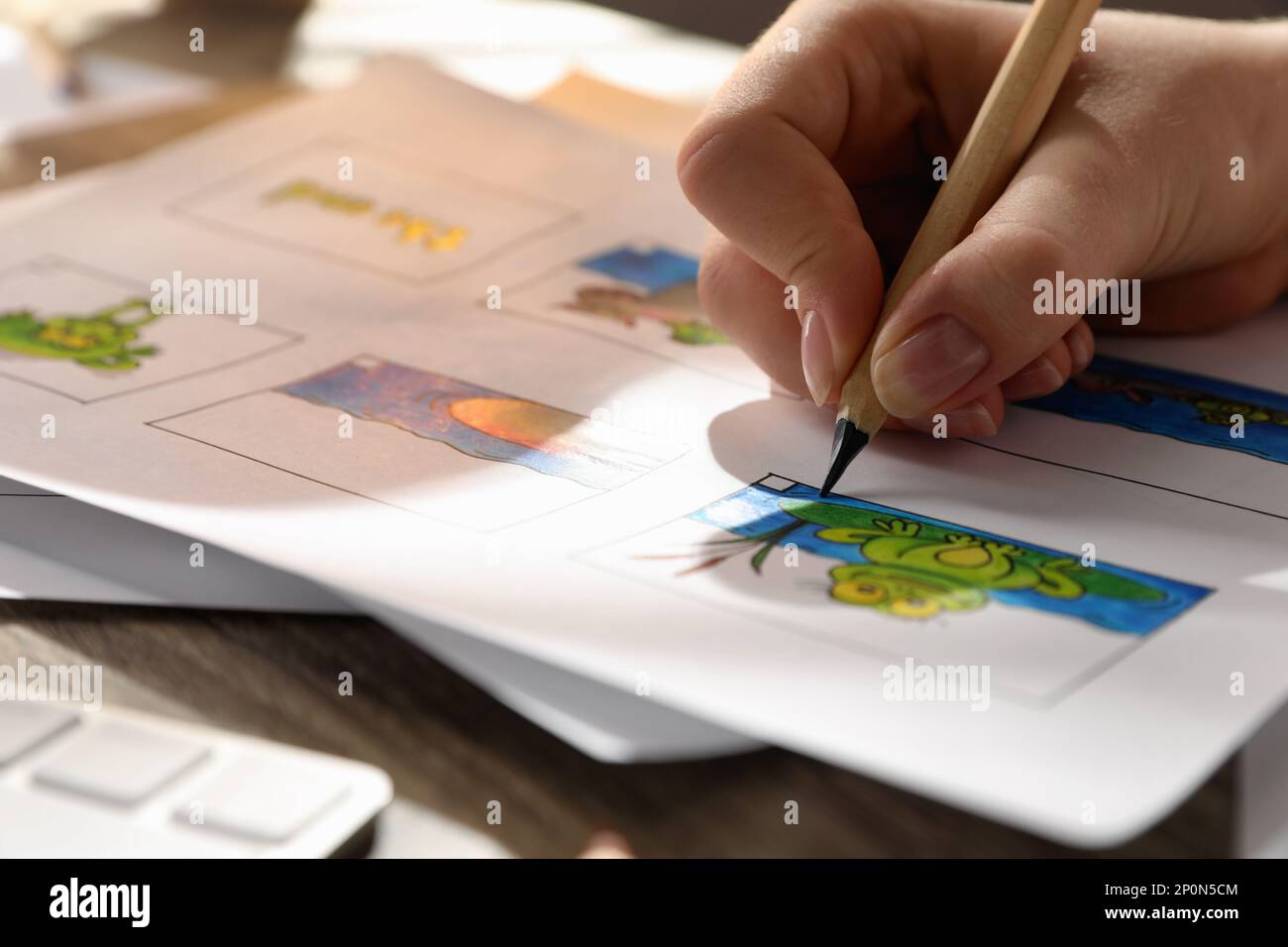 Woman drawing cartoon sketch in storyboard at workplace, closeup. Pre ...