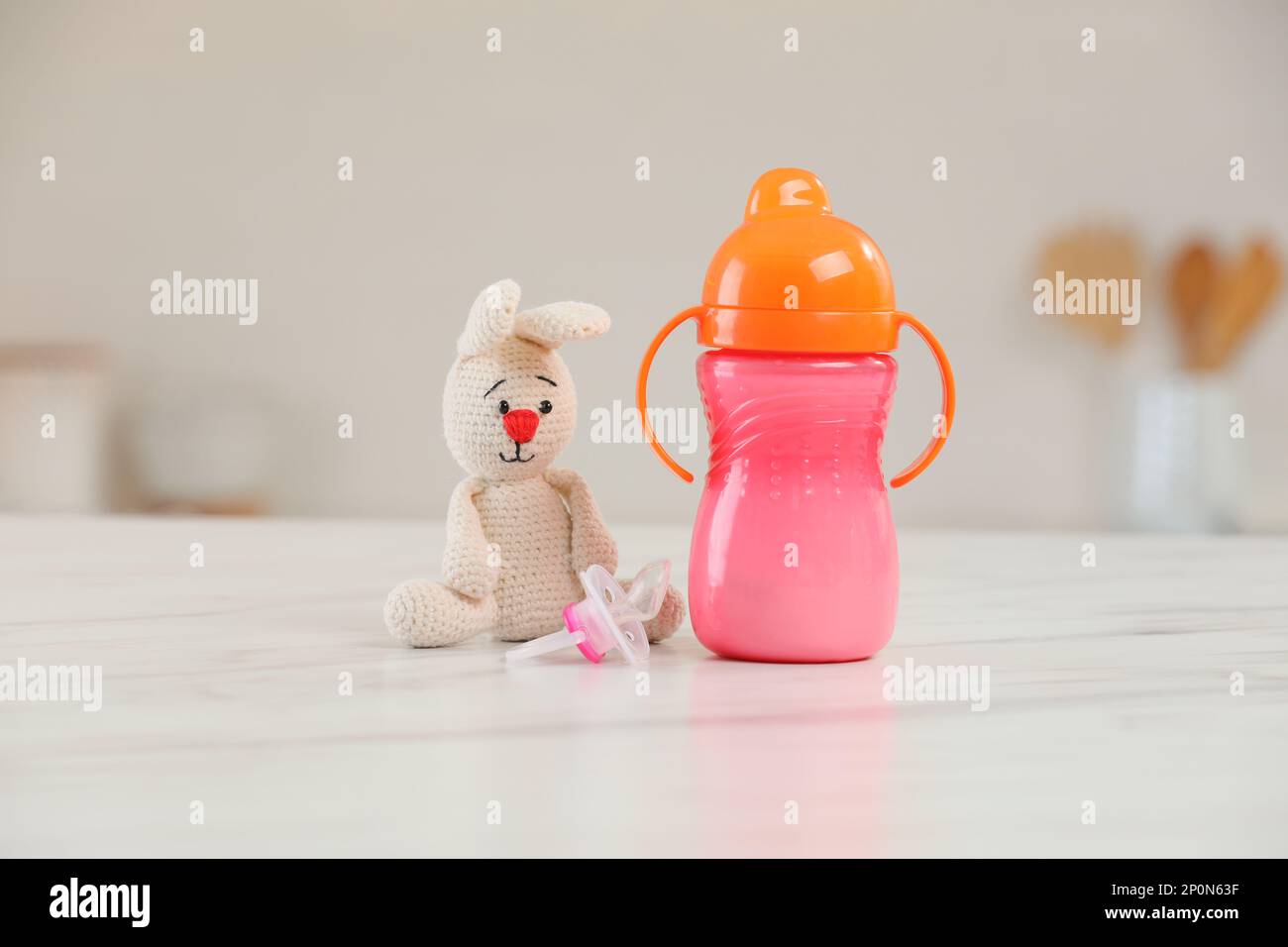 Baby bottle, toy and pacifier on white marble table indoors. Maternity ...