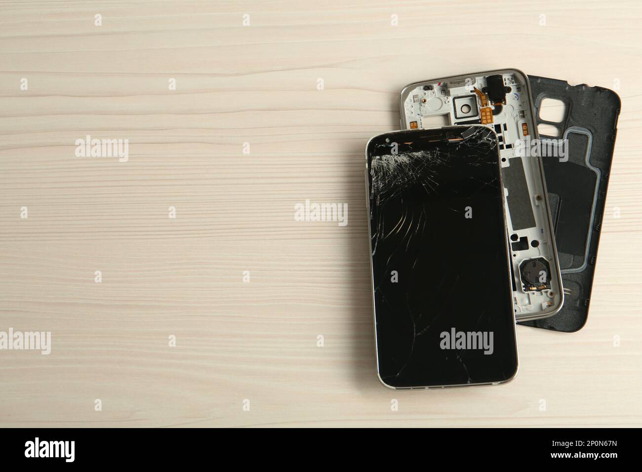 Parts of broken smartphone on white wooden table, flat lay with space ...