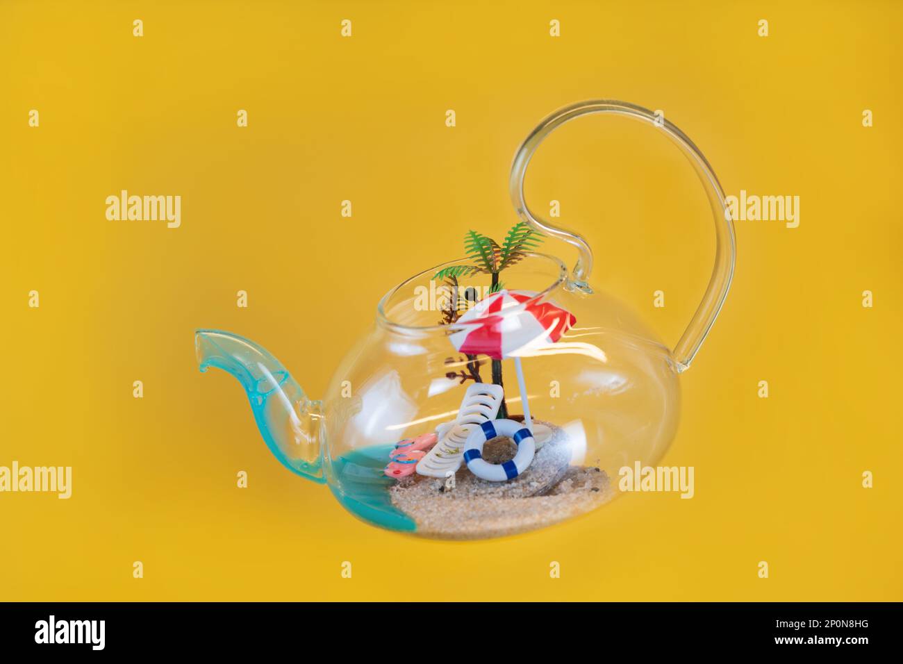 Funny creative summer vacations concept. Transparent tea pot with sand ...