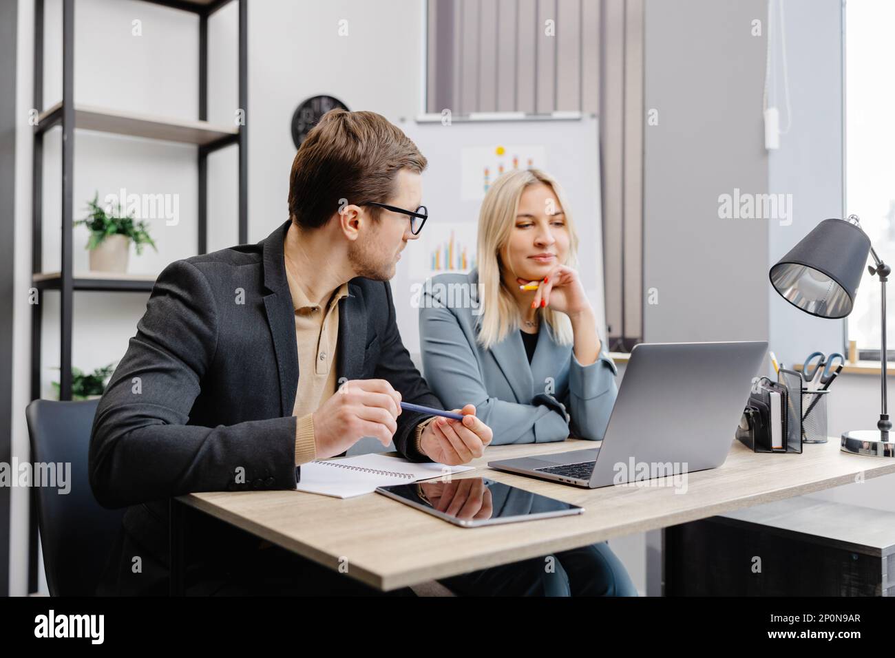 Cheerful business people using a laptop in an office. Young ...
