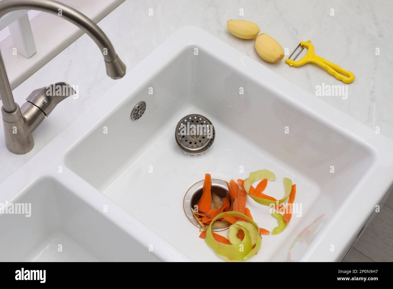 Vegetable scraps in kitchen sink with garbage disposal, above view ...