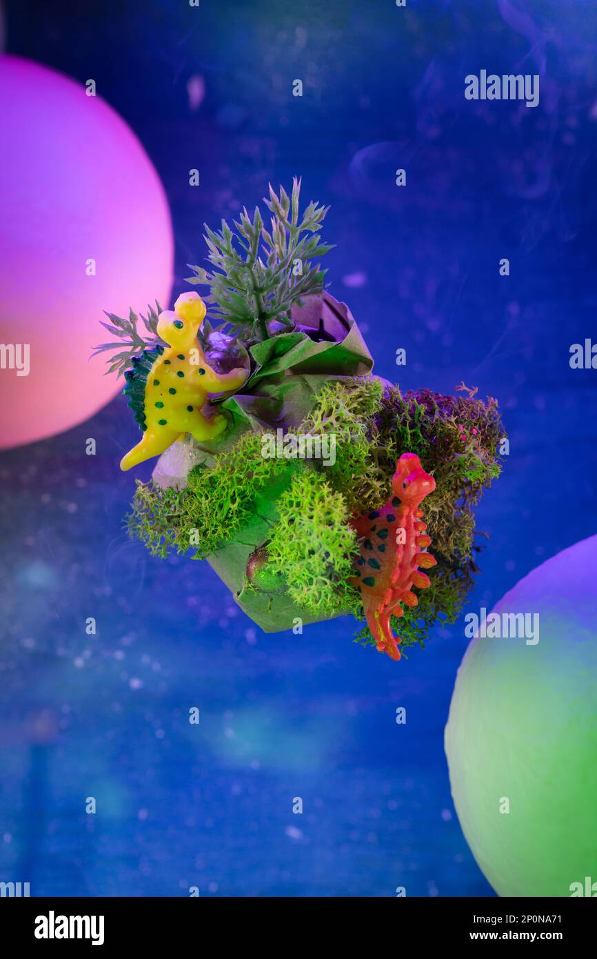 Handmade funny creative planet with colored toy dinos and green grass ...