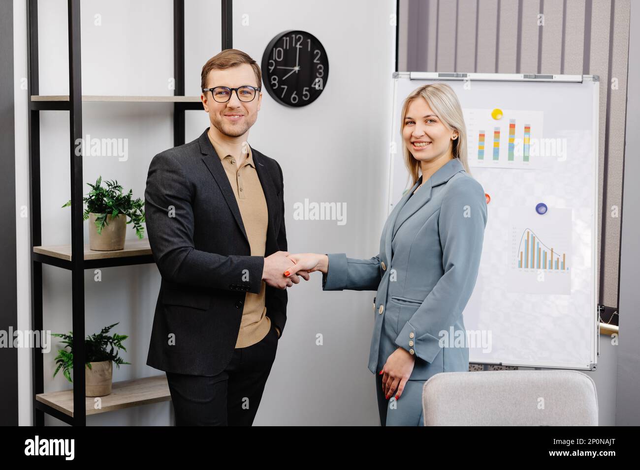 Smiling young female employee shake hand of male colleague make ...