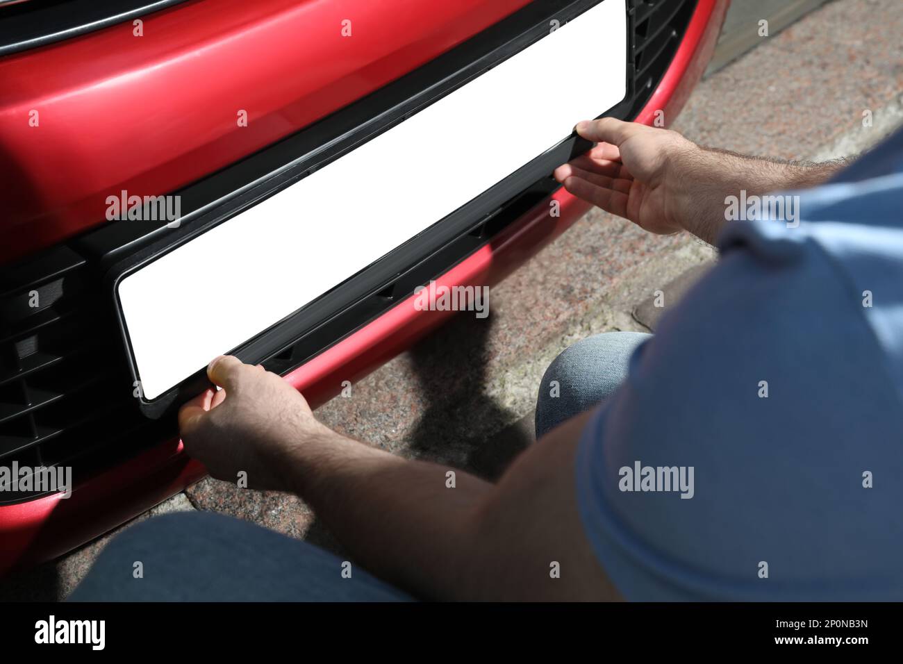 Man installing vehicle registration plate outdoors, closeup. Mockup for ...