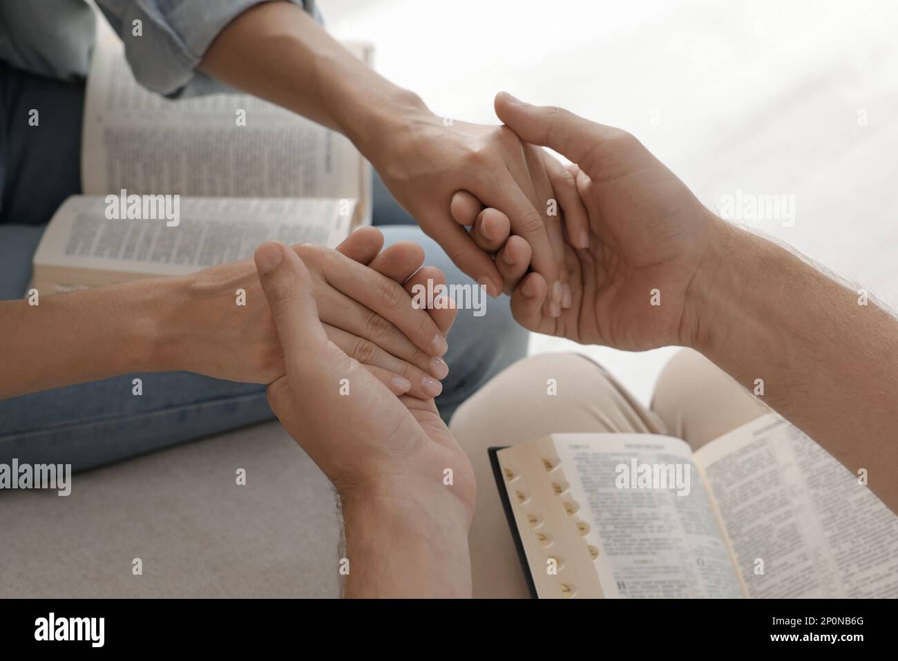 Religious people with Bibles holding hands and praying together indoors ...