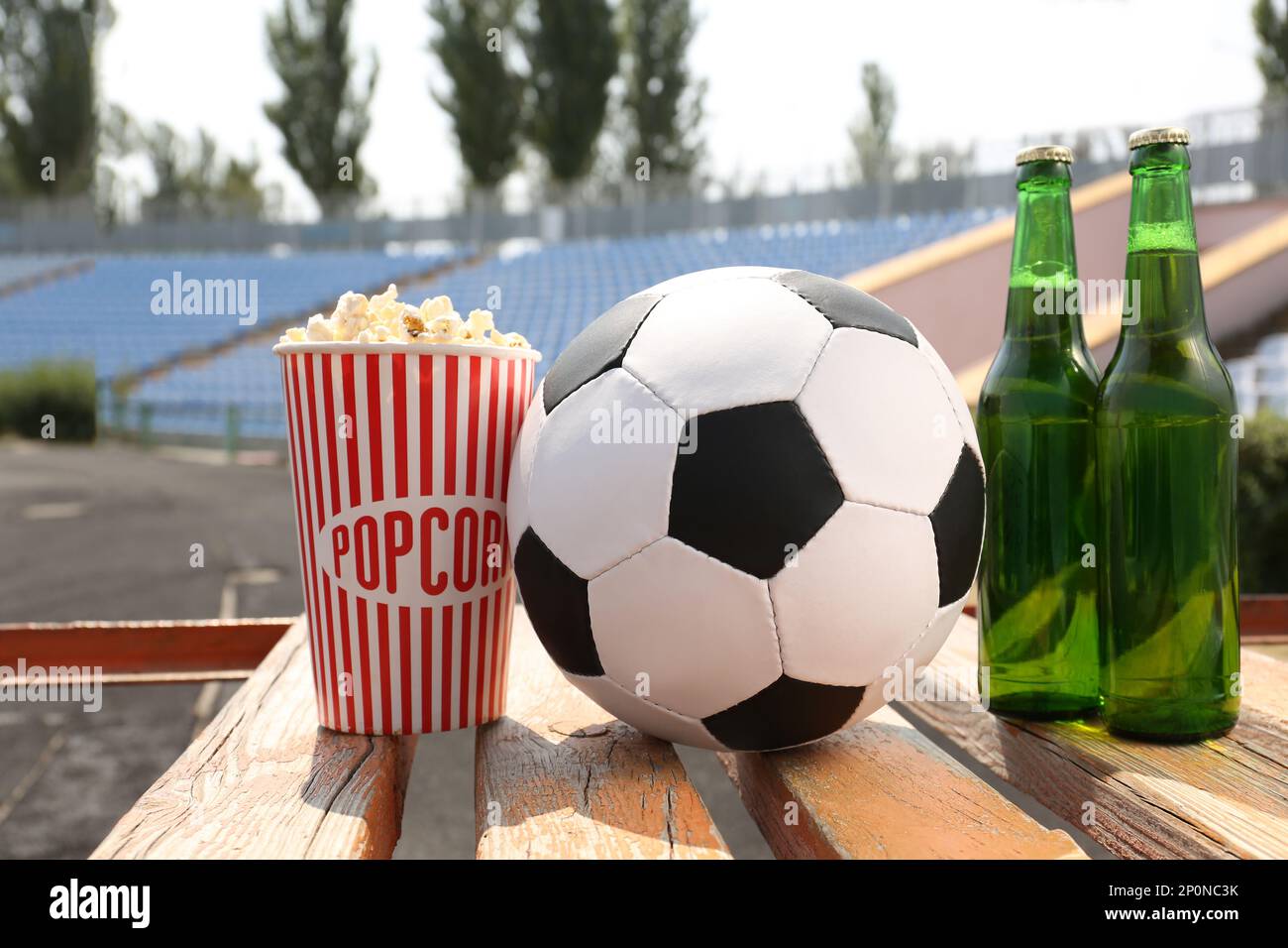 Football ball with beer and popcorn on wooden bench in stadium Stock ...