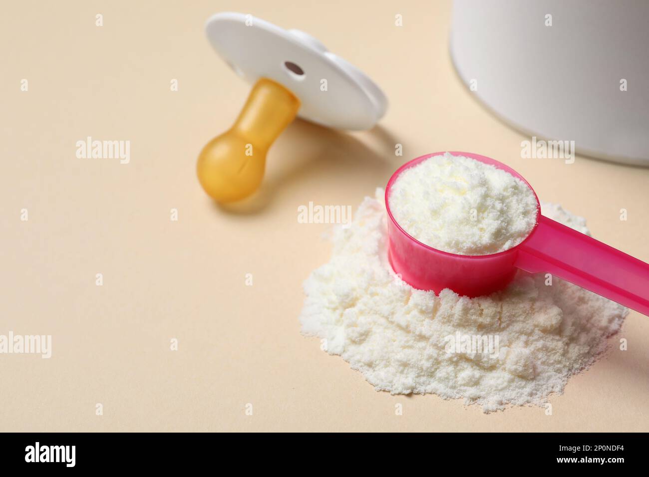 Powdered infant formula with scoop and pacifier on beige background ...