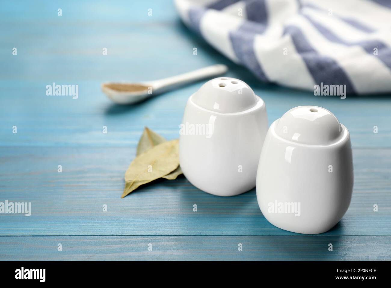 White ceramic salt and pepper shakers with bay leaves on turquoise ...