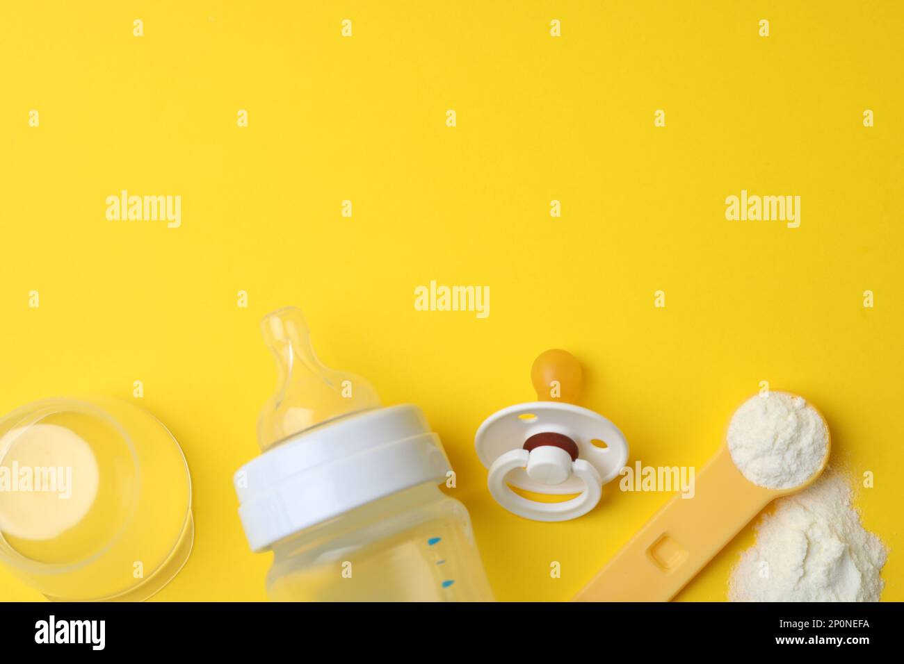 Flat lay composition with powdered infant formula on yellow background ...