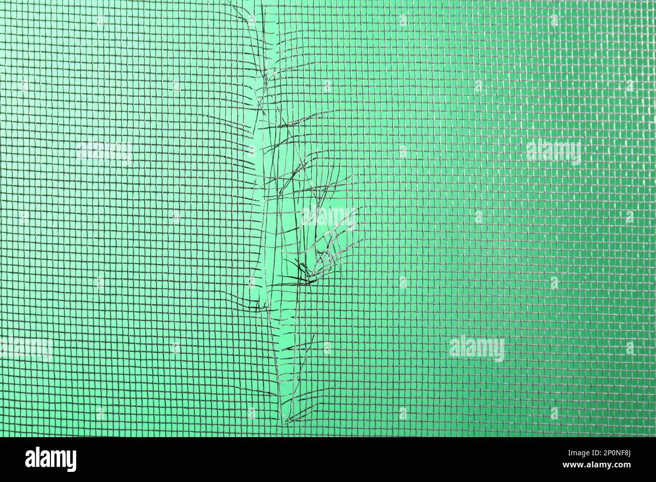 Torn window screen against green background, closeup Stock Photo - Alamy