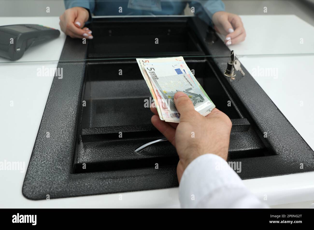 Cashier giving money to woman at currency exchange window in bank ...