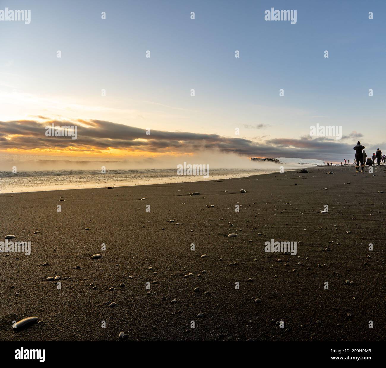 Reynisfjara black sand beach at sunset illuminated by the last rays of ...
