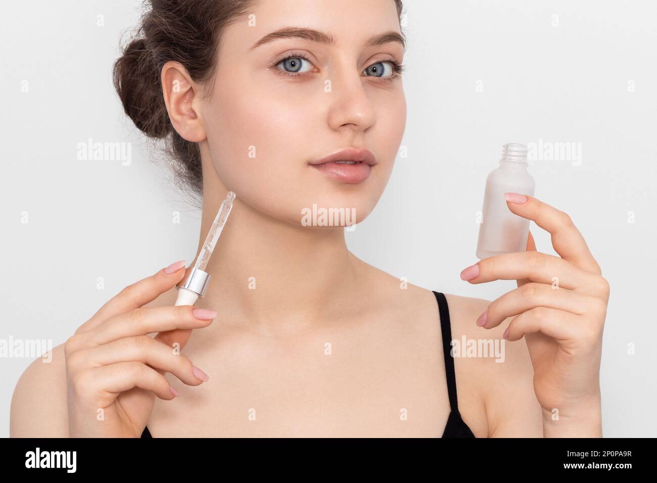 Beautiful young girl with bottle and a pipette of collagen serum in her ...