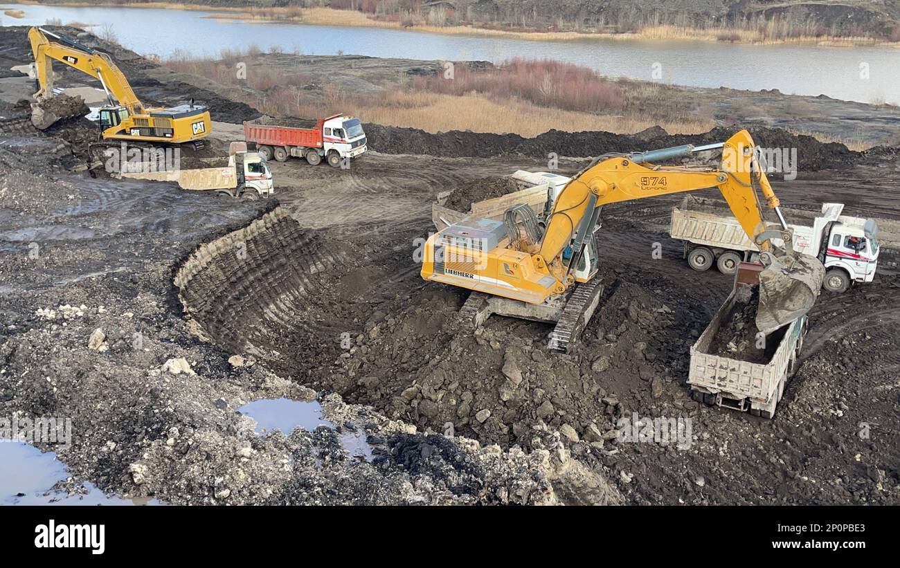 Excavators are loading continuously the trucks, working at a huge ...